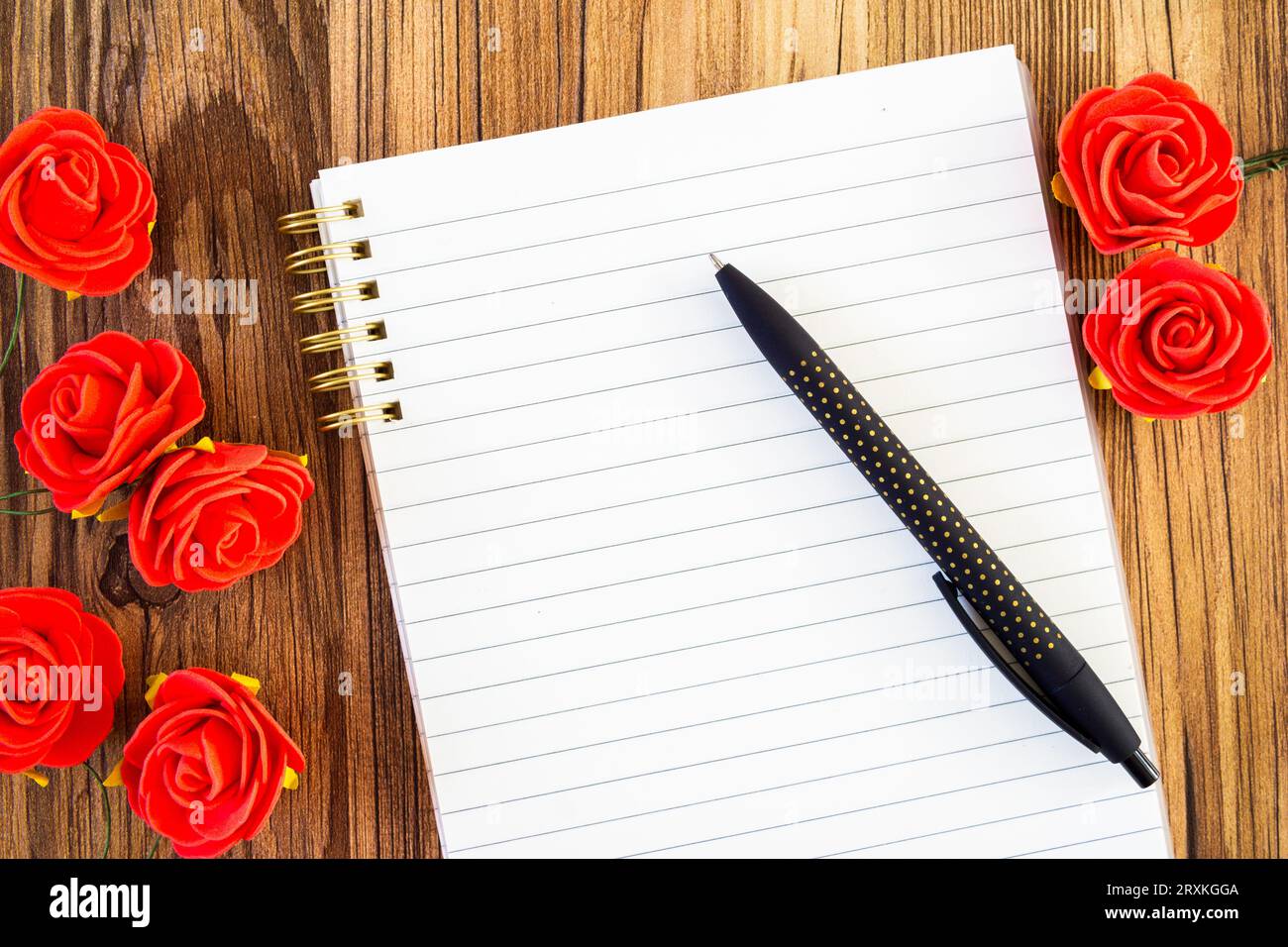 black pen on lined blank note pad mock up on wooden background red rose ...