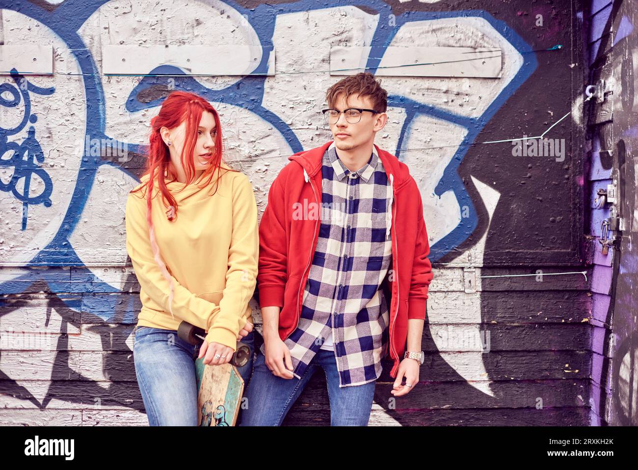 Teenage friends leaning on graffiti covered wall Stock Photo - Alamy