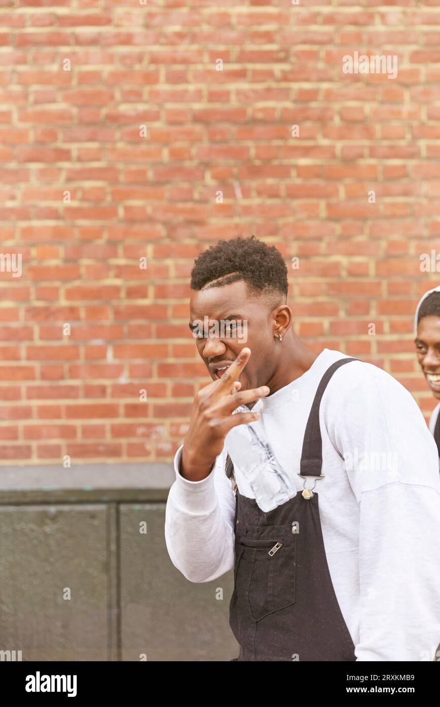 Young man making gang sign Stock Photo - Alamy