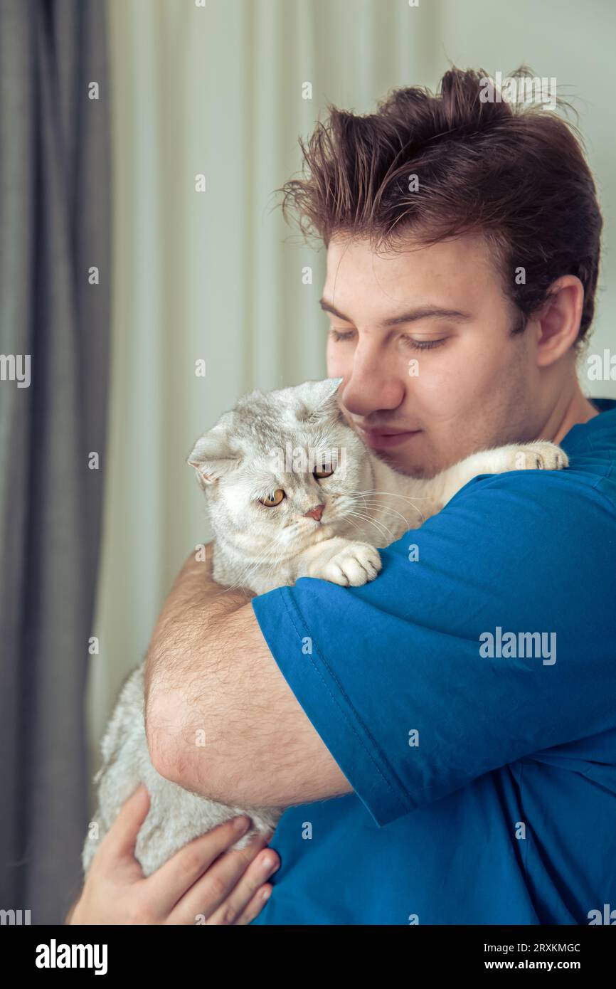 Close-up of the face of a man holding his cute purring British cat. The ...