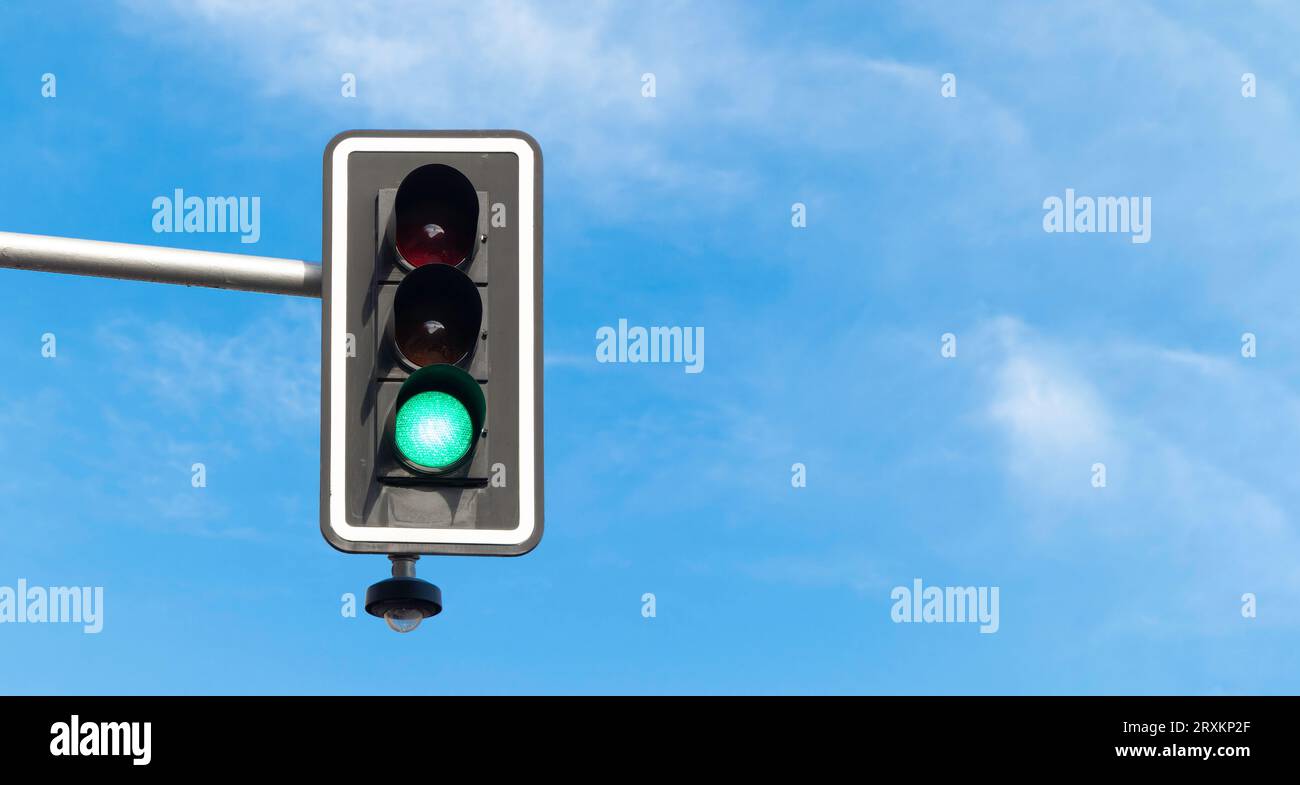 Traffic light on green, with blue sky and clouds on the background ...