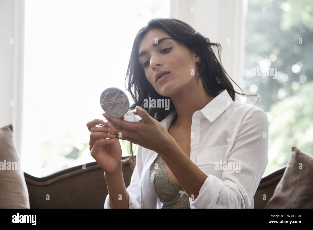 Woman applying makeup using a handheld mirror Stock Photo - Alamy