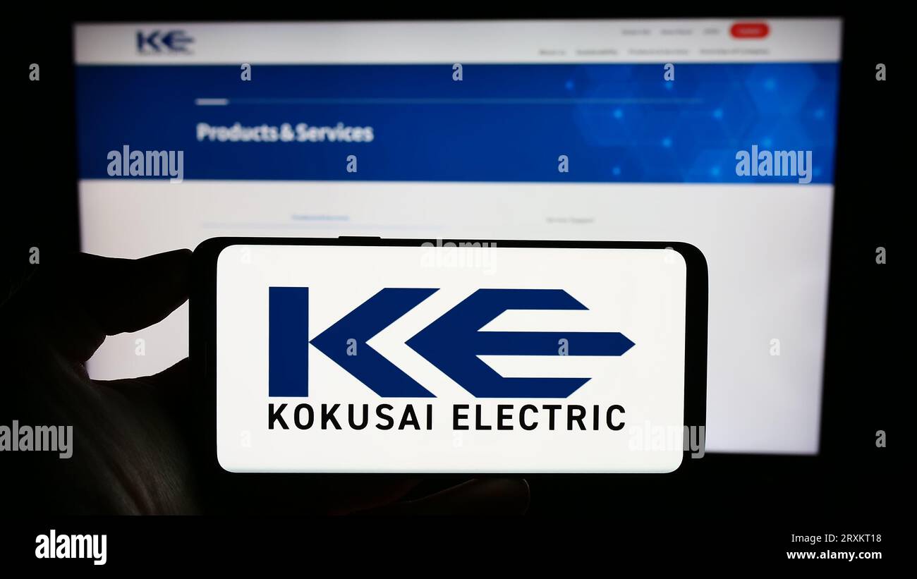 Person holding mobile phone with logo of Japanese company Kokusai ...