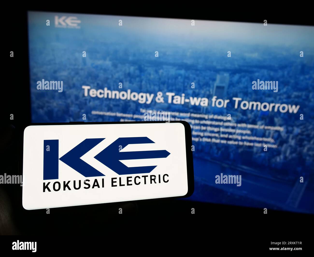 Person holding cellphone with logo of Japanese company Kokusai Electric ...