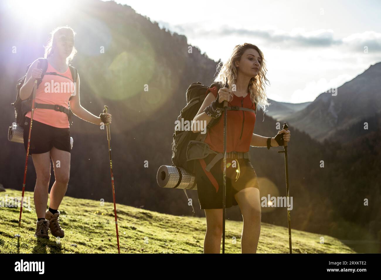 Young women hiking beneath mountains and sunshine Stock Photo - Alamy