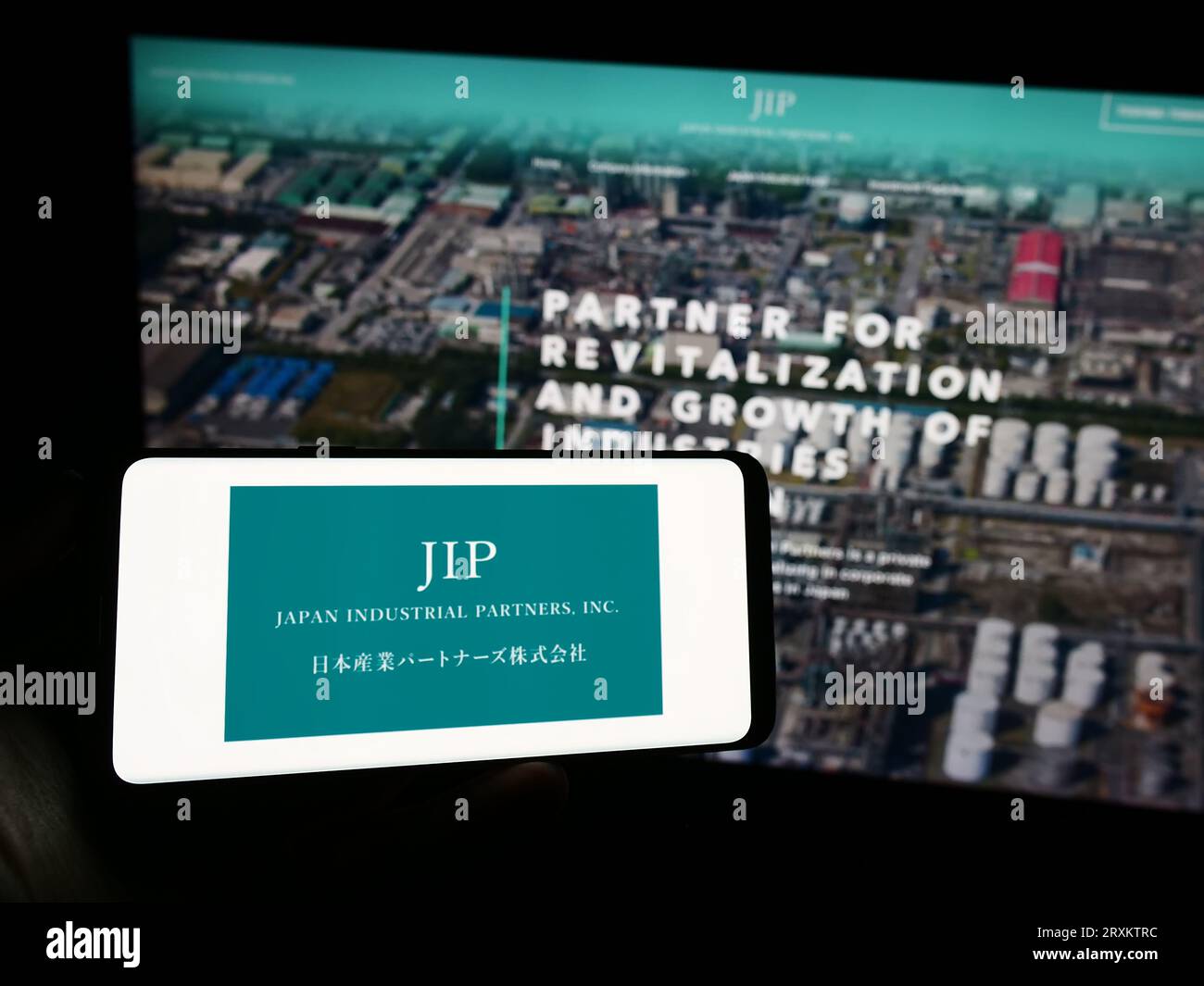 Person holding mobile phone with logo of company Japan Industrial ...