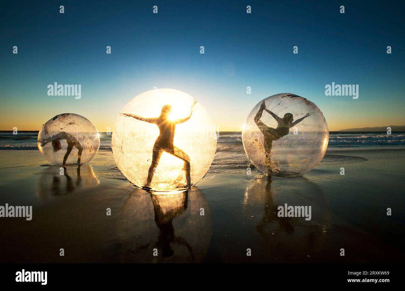 Silhouetted figures inside bubbles on the beach at sunset Stock Photo ...