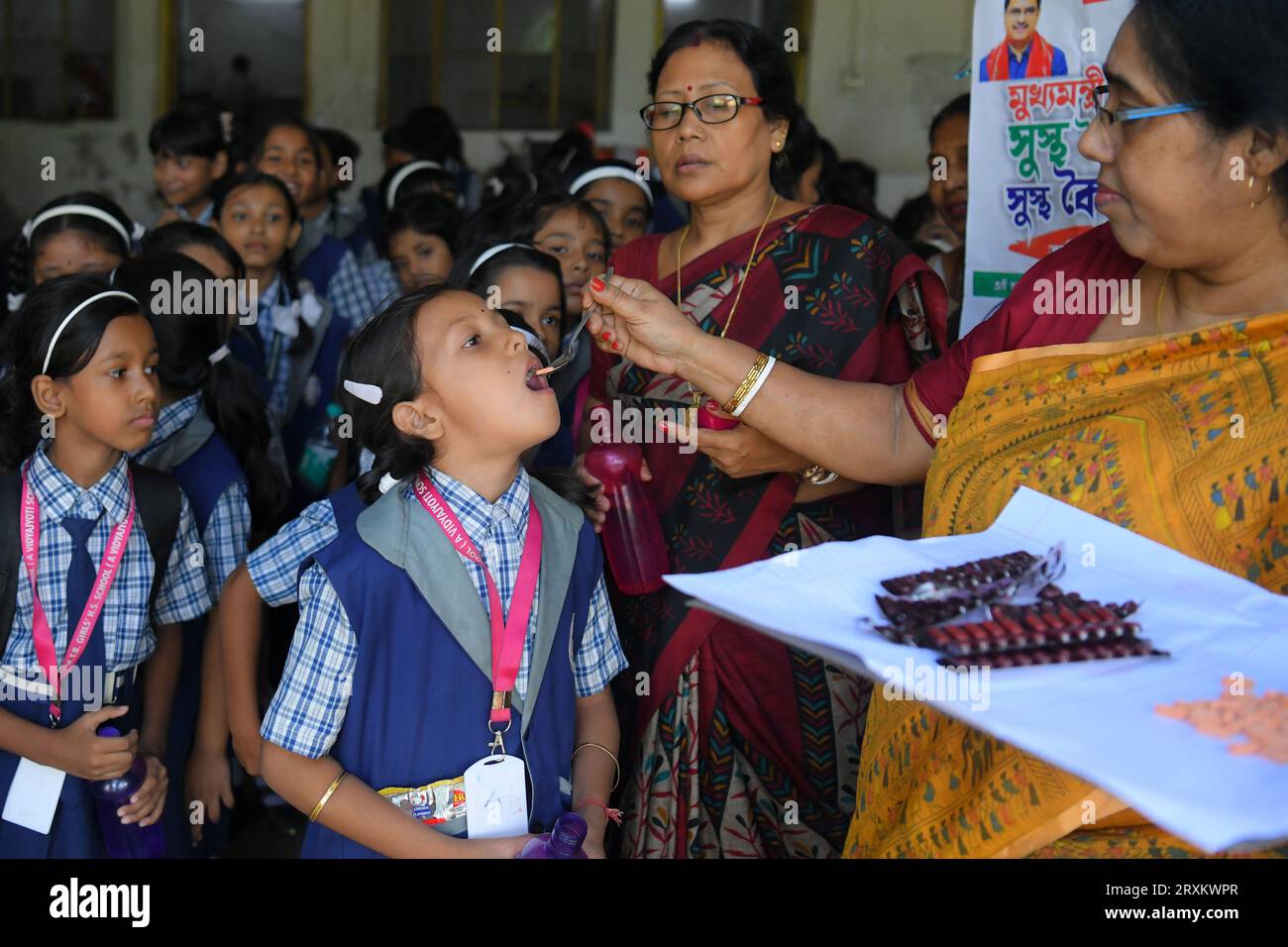 A schoolteacher is giving deworming tablets to the students in a school ...