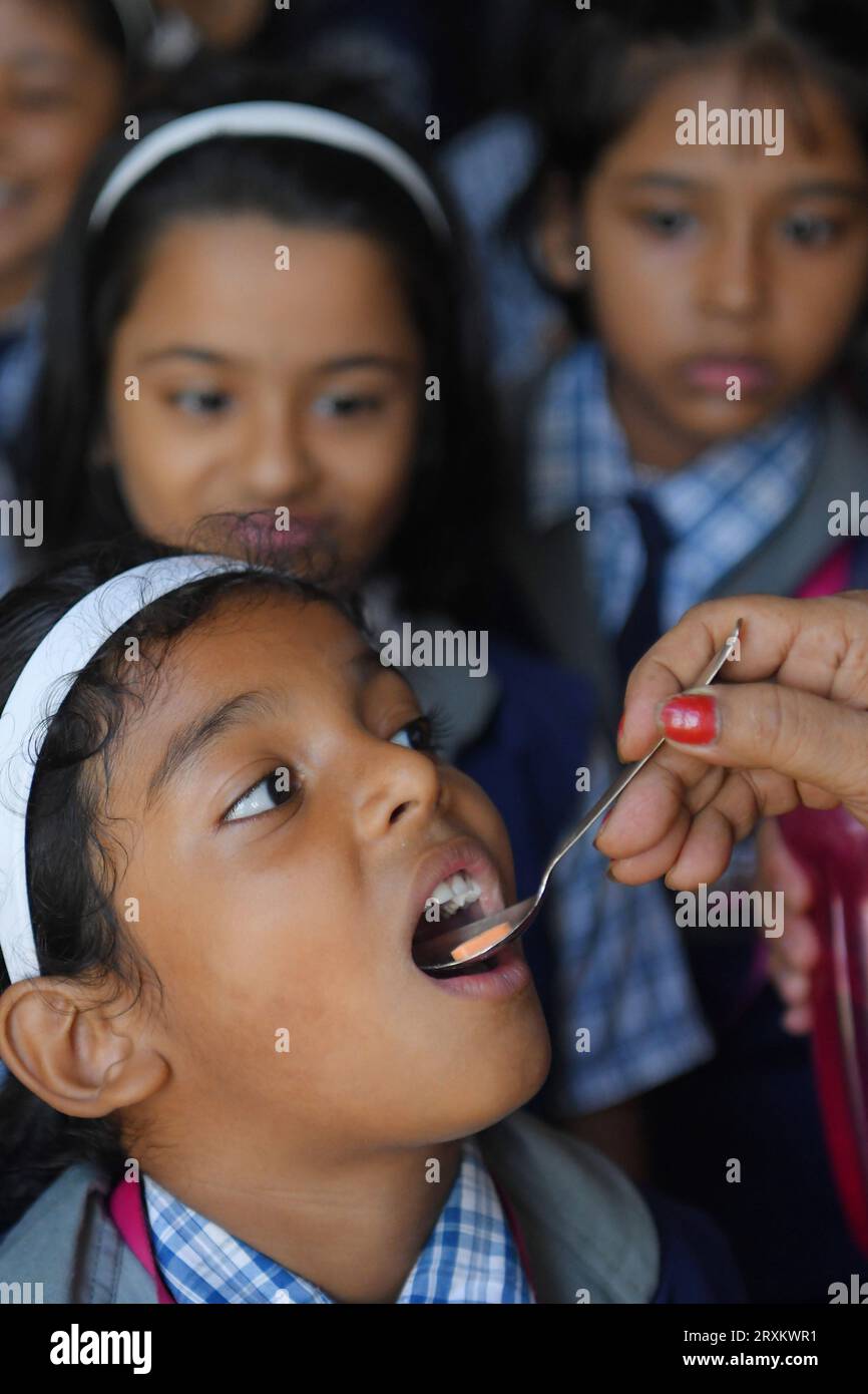 A schoolteacher is giving deworming tablets to the students in a school ...