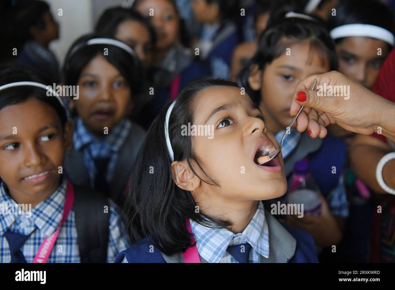 A schoolteacher is giving deworming tablets to the students in a school ...