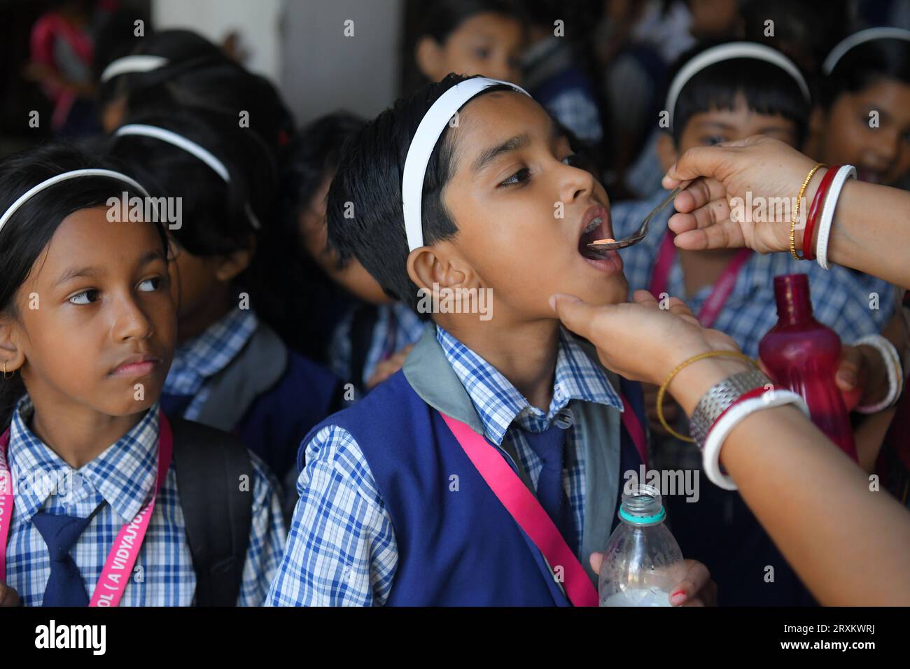 A schoolteacher is giving deworming tablets to the students in a school ...