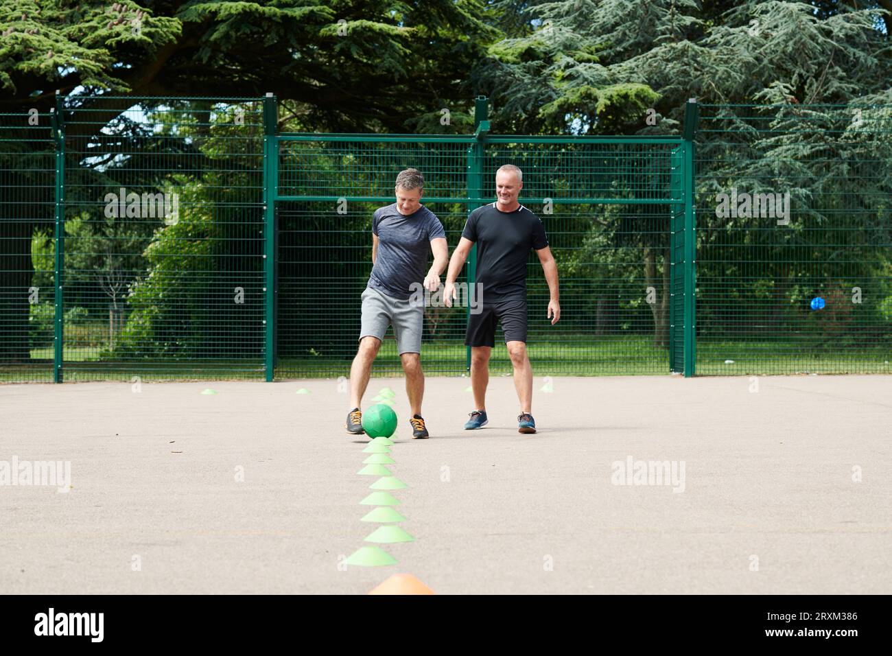 Mature men kicking ball on court Stock Photo - Alamy