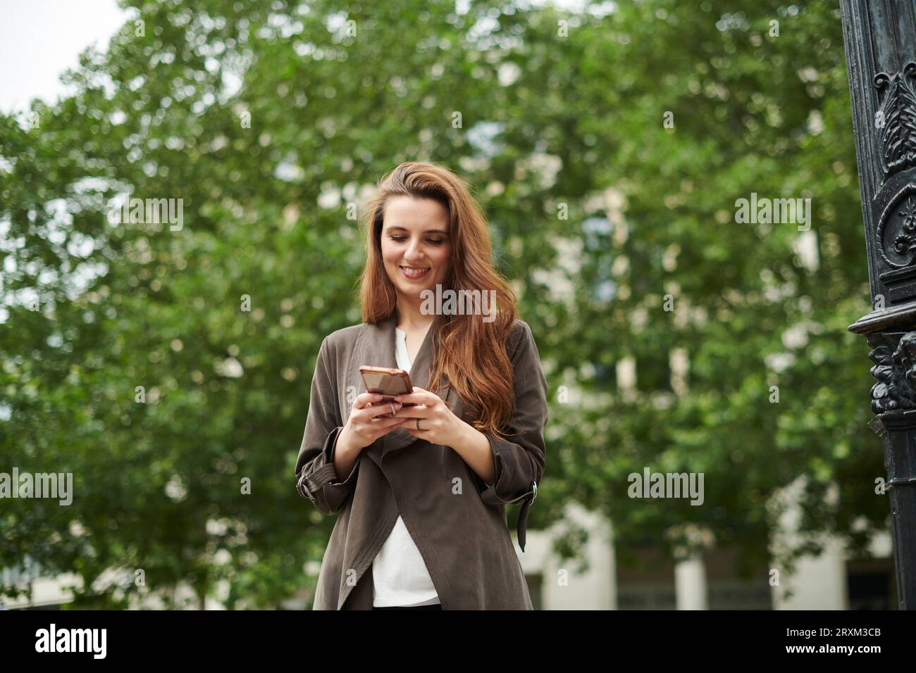 Mid adult woman smiling while texting on smart phone Stock Photo - Alamy