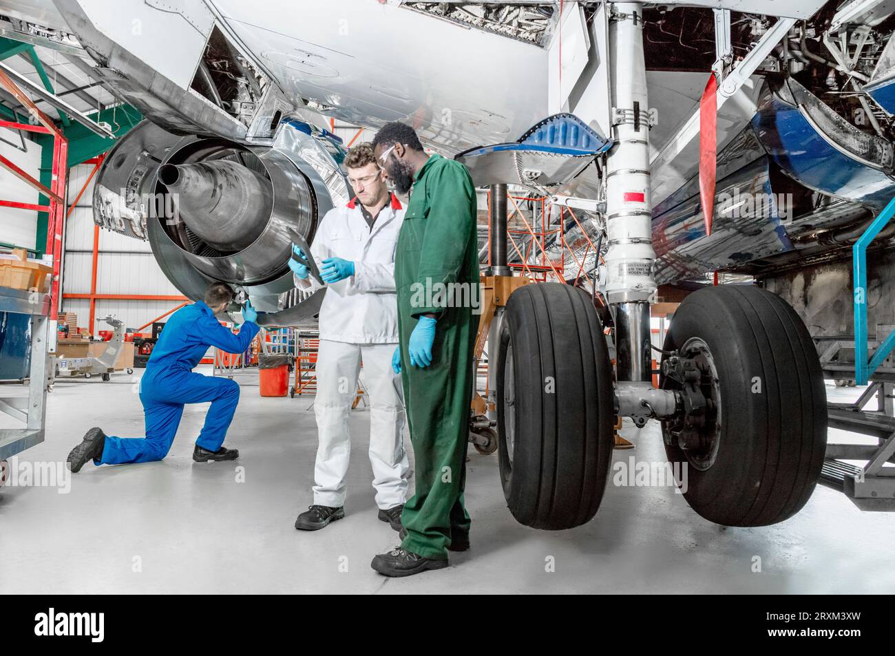Men using digital tablet by airplane wheels in hangar Stock Photo - Alamy