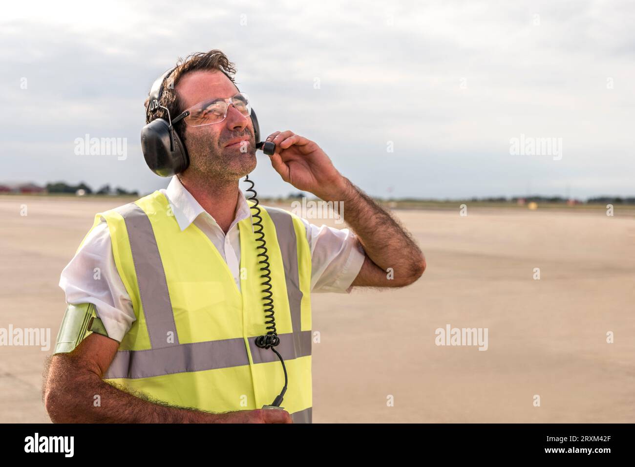 Man wearing headset on airport runway Stock Photo - Alamy