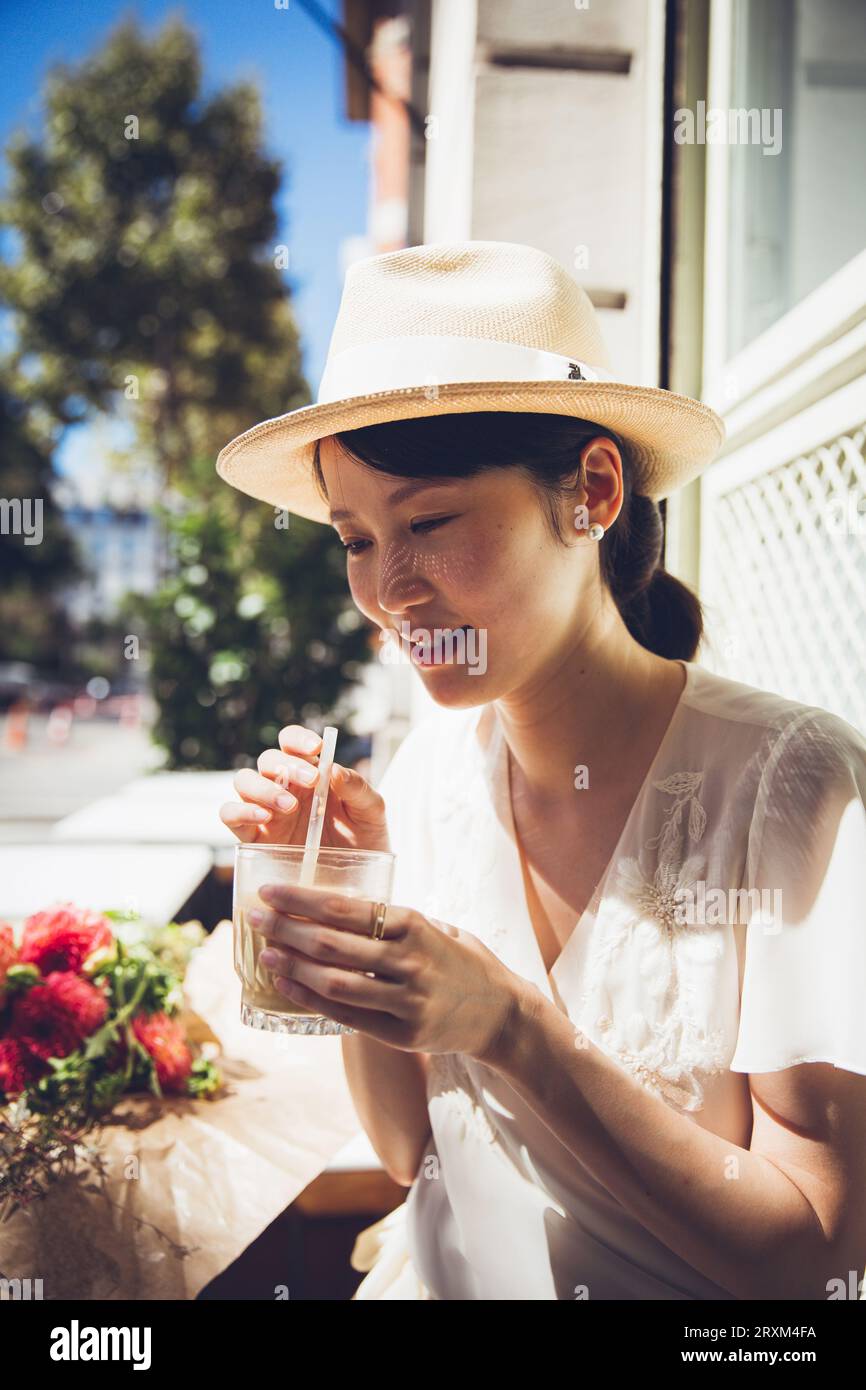Young woman wearing straw hat holding iced coffee Stock Photo - Alamy
