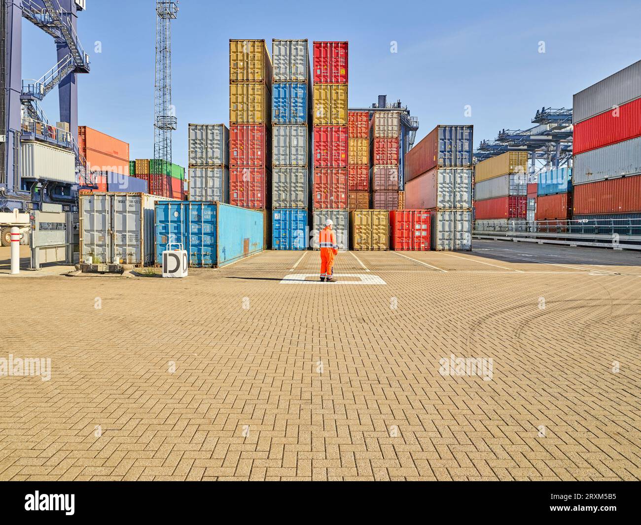 Dock worker by stack of cargo containers Stock Photo - Alamy
