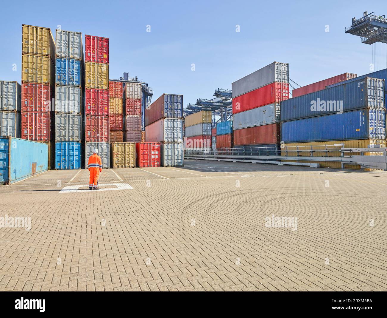 Dock worker by stack of cargo containers Stock Photo - Alamy