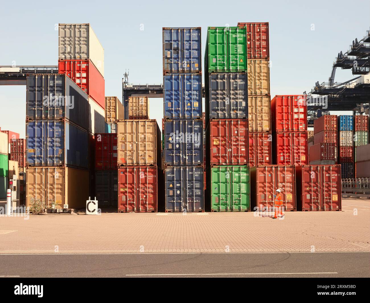 Dock worker by stack of cargo containers Stock Photo - Alamy