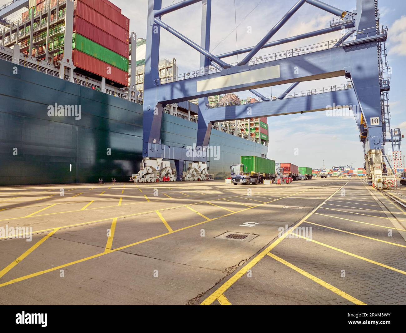 Trucks with cargo containers beneath dock crane Stock Photo - Alamy