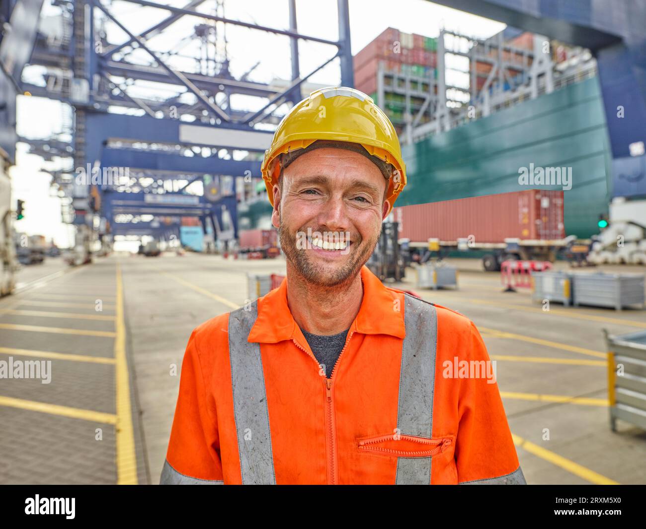 Smiling dock worker in reflective clothing and hard hat Stock Photo - Alamy