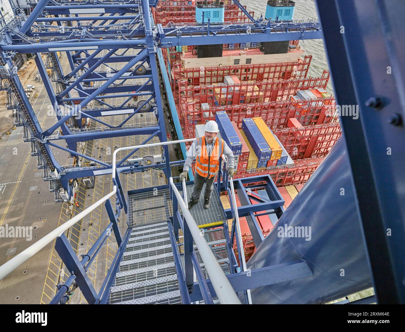 Dock worker climbing steps of crane Stock Photo - Alamy