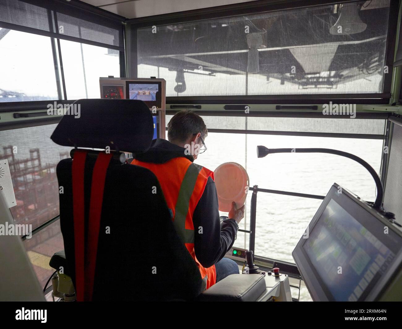 Dock worker sitting in seat of crane Stock Photo - Alamy