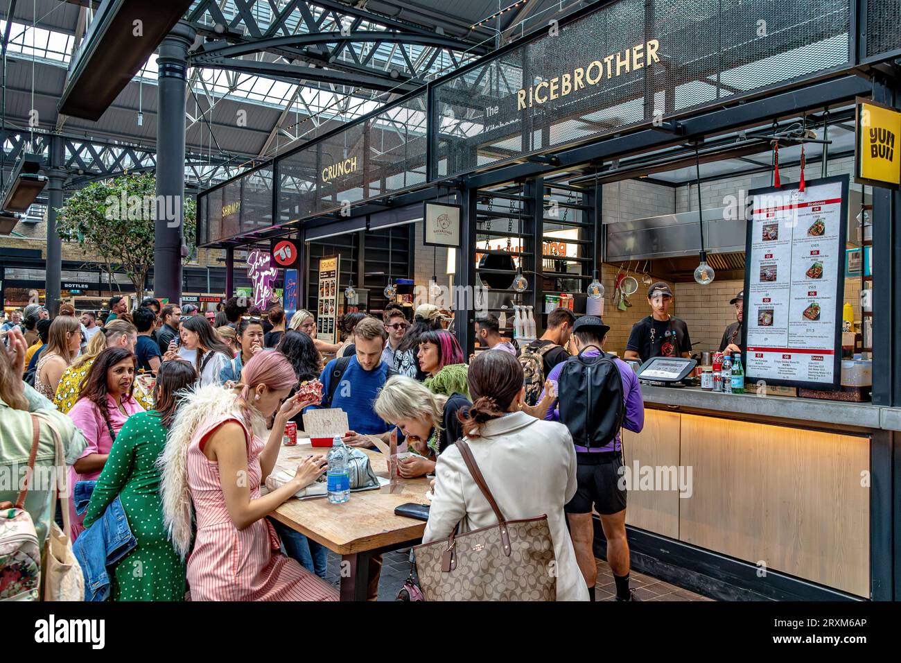 People sitting down eating food at tables near various diverse food ...