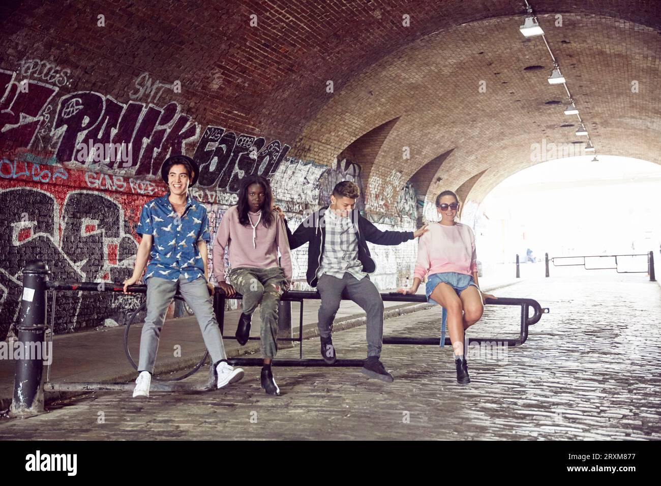 Teenage friends sitting on gate in tunnel Stock Photo - Alamy