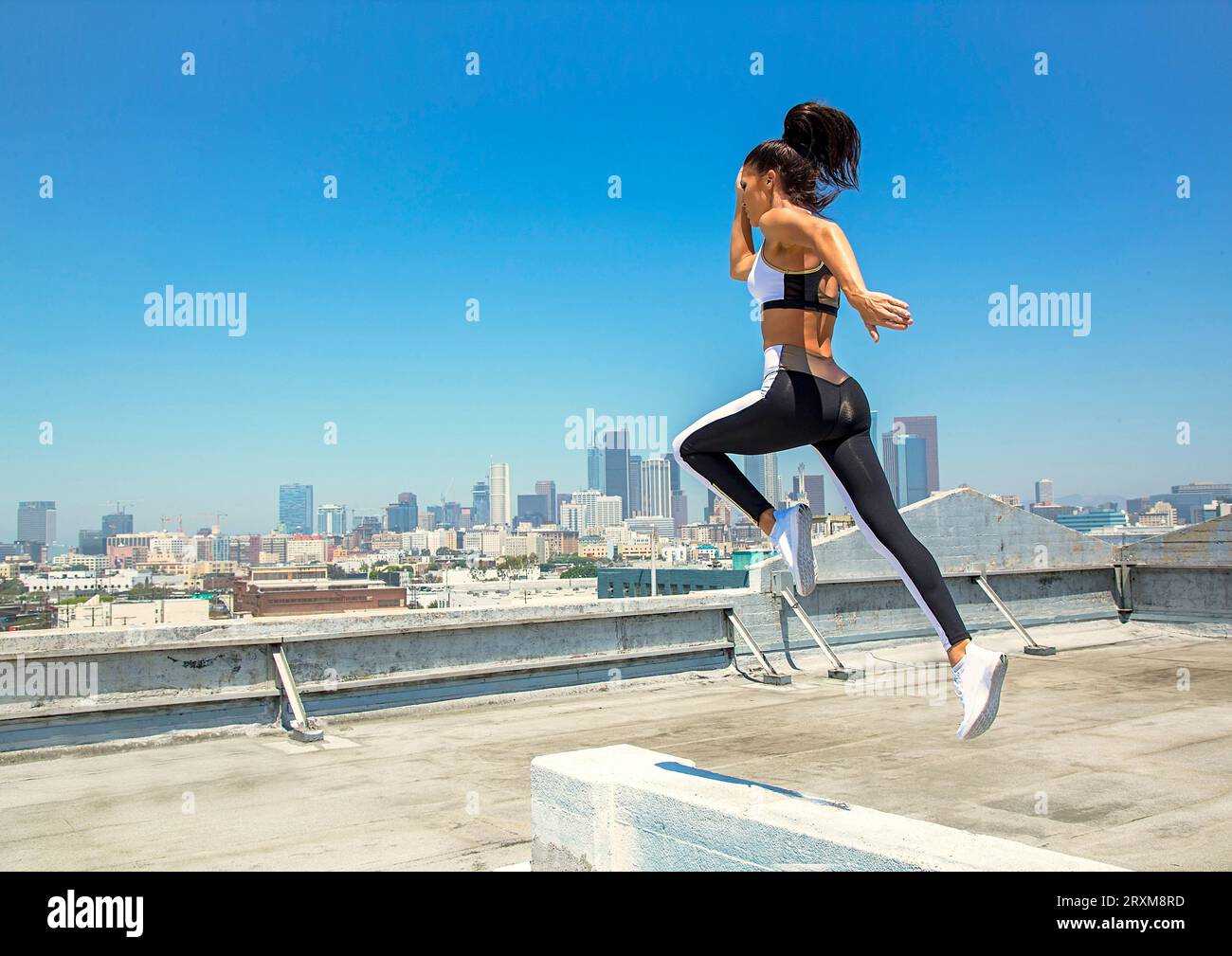 Young woman running on rooftop beam Stock Photo - Alamy