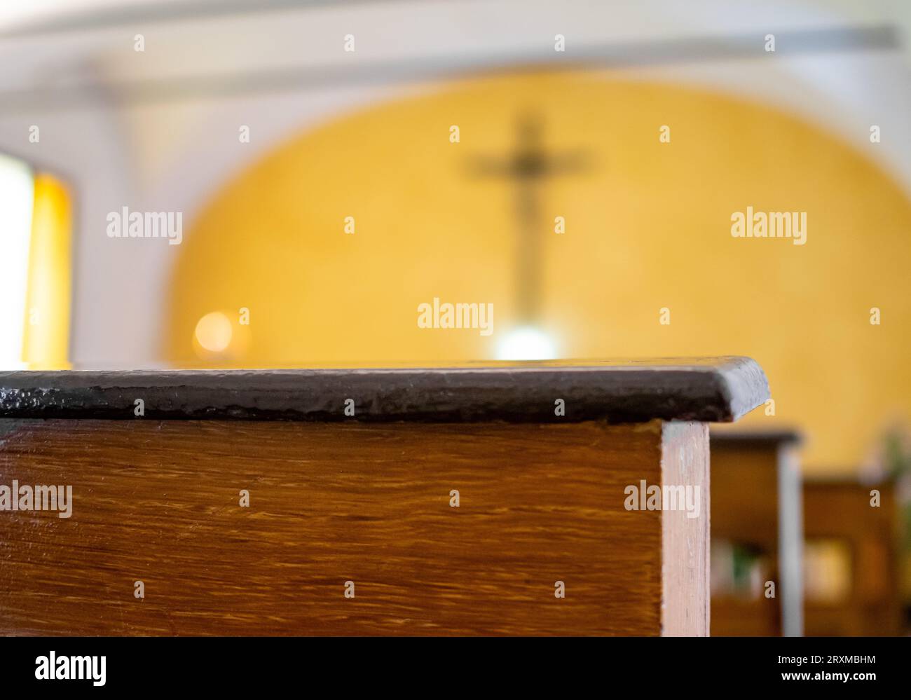 Dark brown church pews with light yellow background of altar and ...