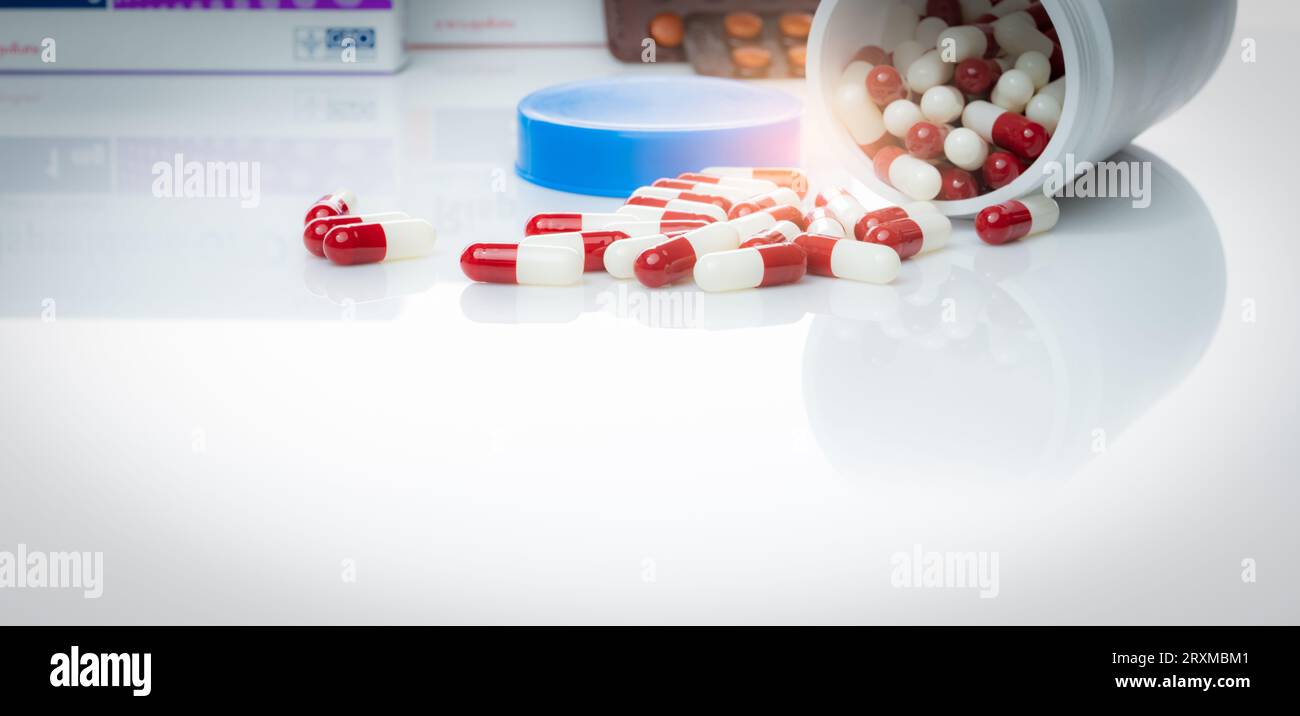 Red and white capsules pill spilled out from white plastic bottle ...