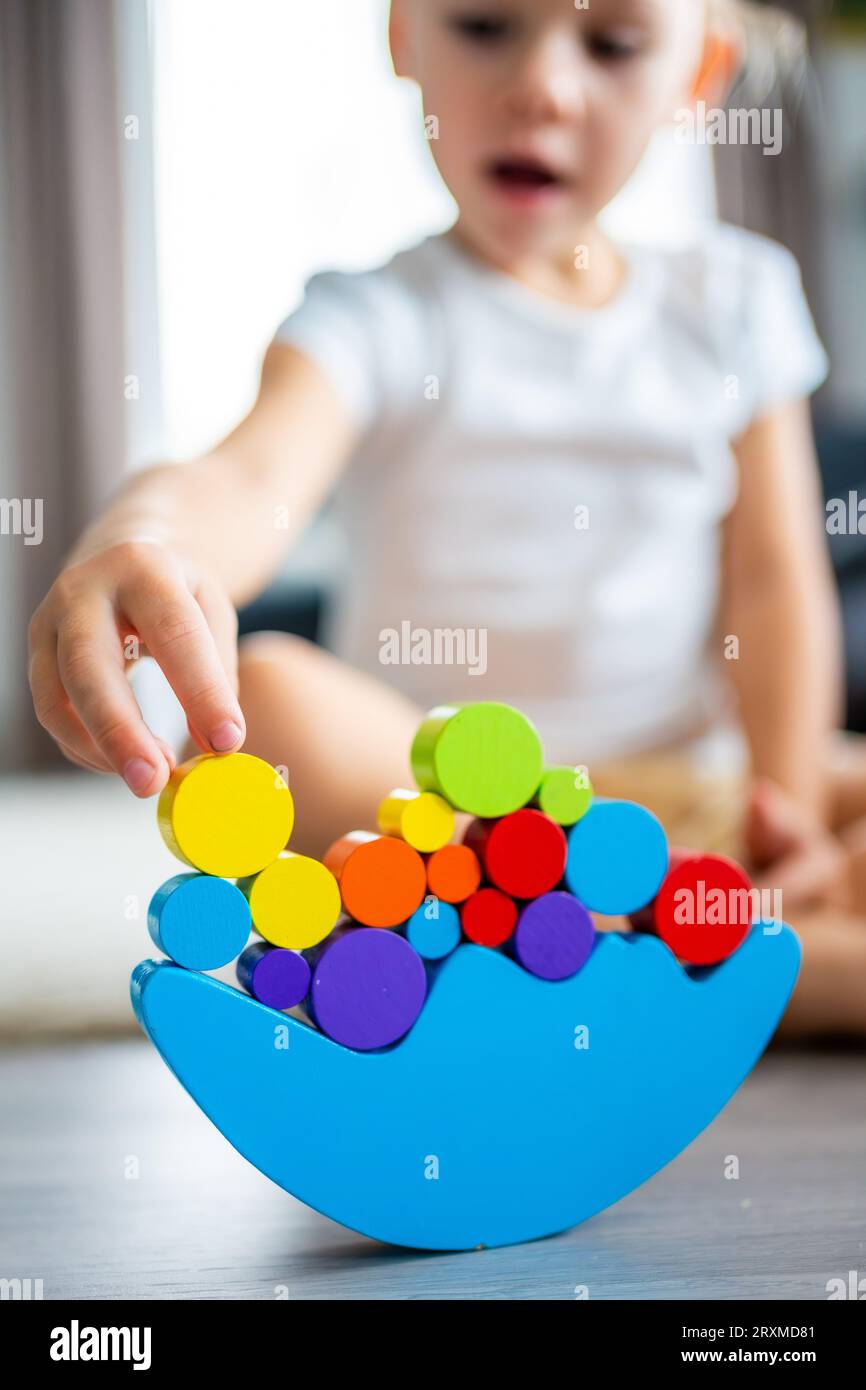 Little girl playing with wooden balancing toy on the floor in home ...