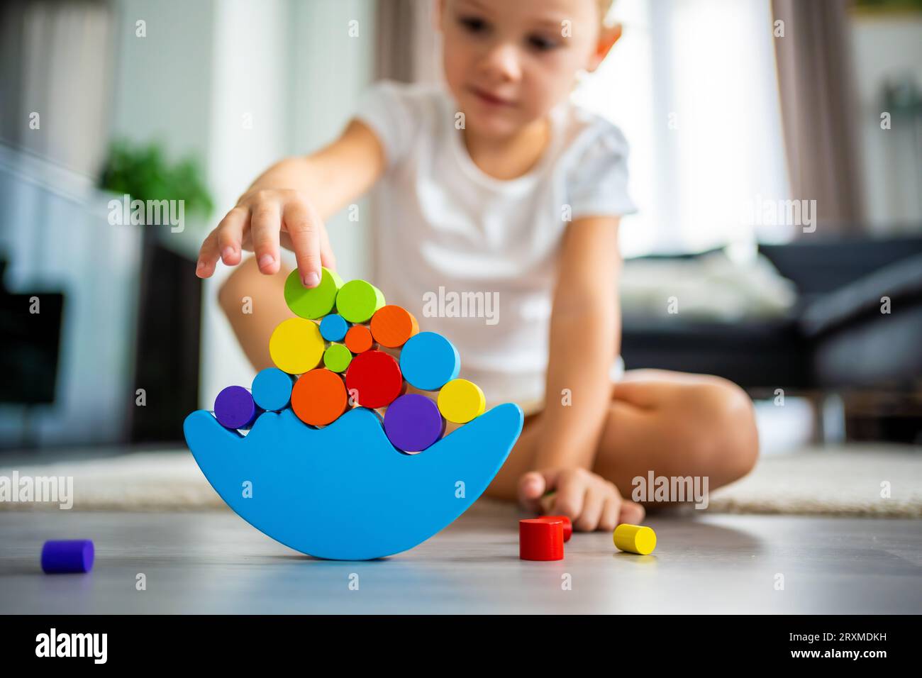 Little girl playing with wooden balancing toy on the floor in home ...