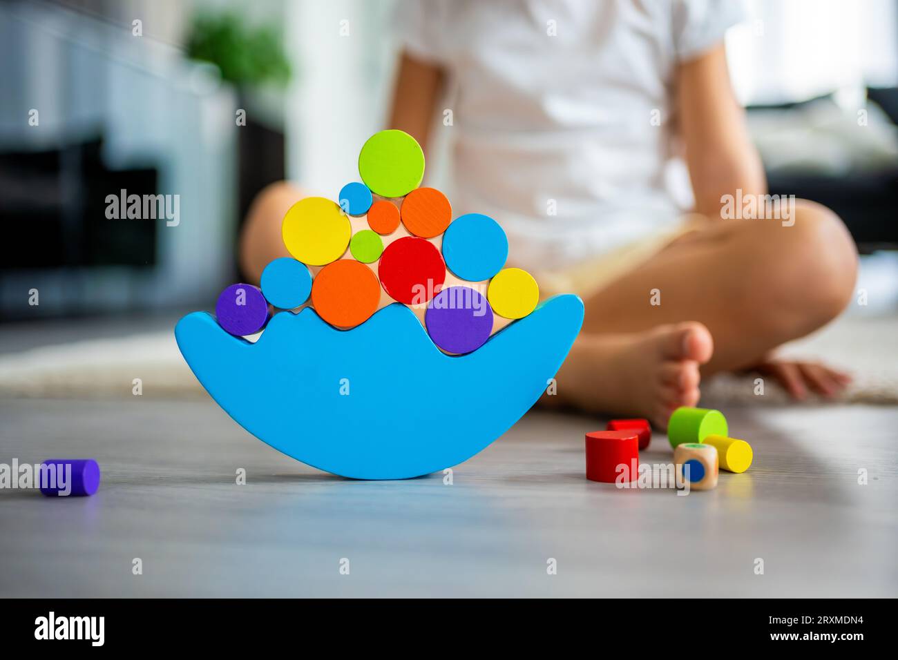 Little girl playing with wooden balancing toy on the floor in home ...