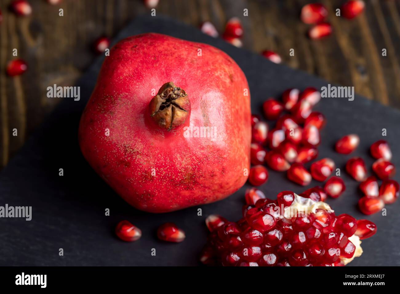 A small ripe red pomegranate is lying on the table, a ripe red ...