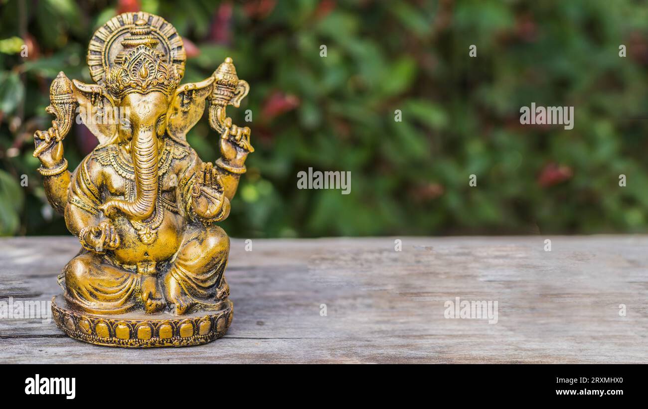Ganesha statue sitting in meditating yoga pose on a trunk. Copy space ...