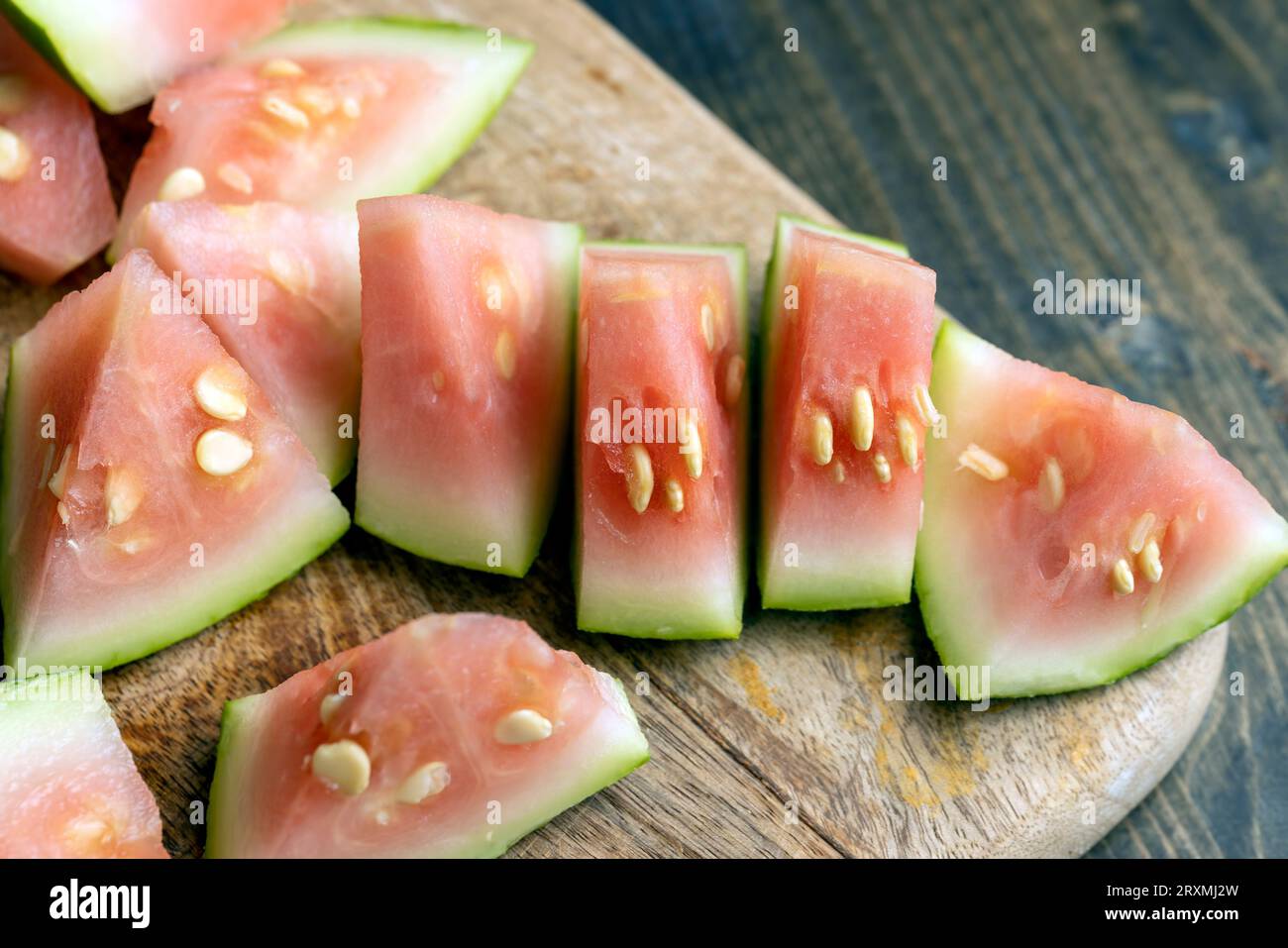 Unripe watermelon of small size with large white seeds and light pink ...