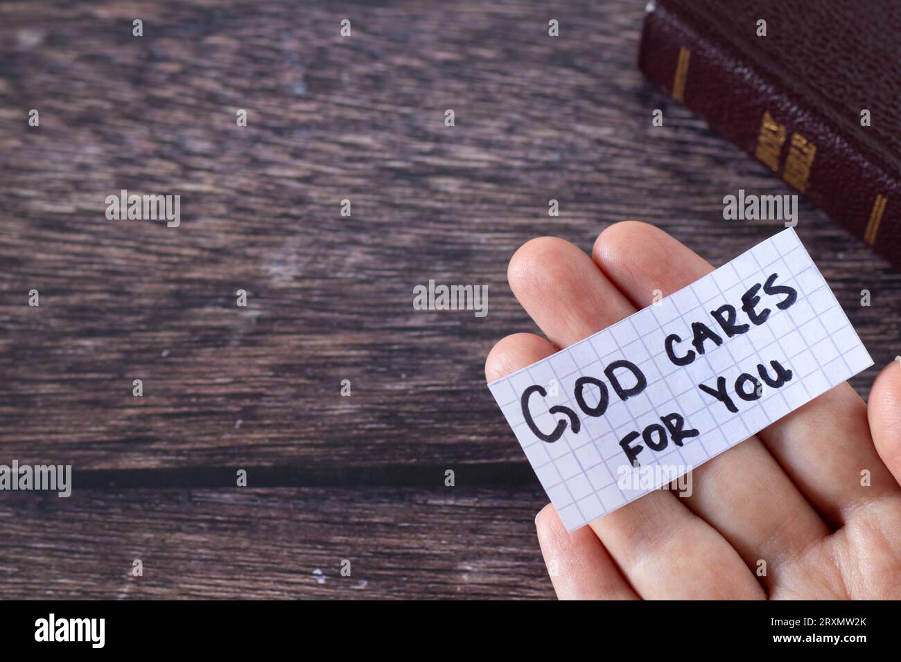 God cares for you, handwritten text note on human hand and holy bible ...
