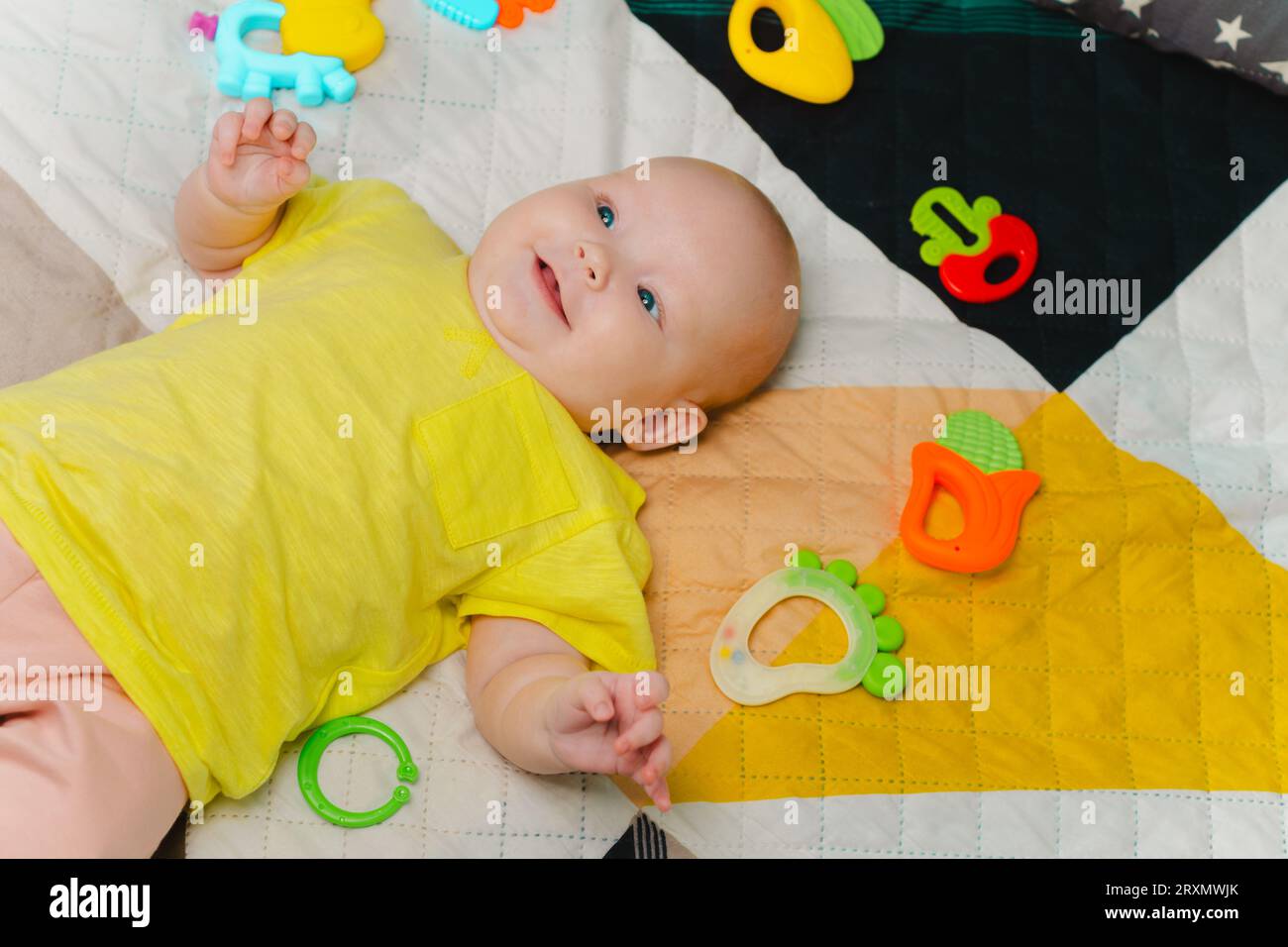 Cute little newborn baby surrounded by colorful toys, lying at home on ...