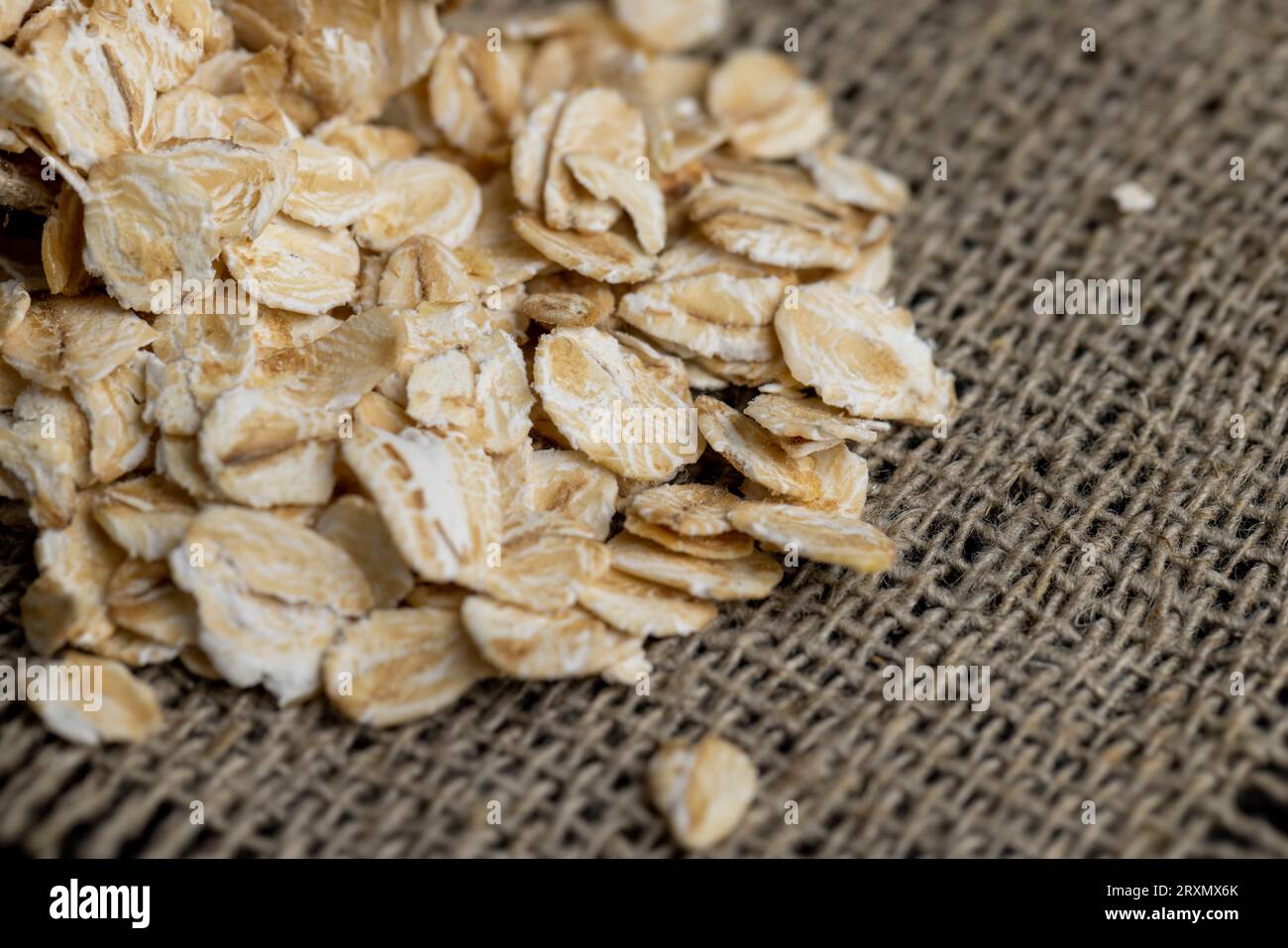 Oat flakes scattered on coarse linen fabric, dry processed oat flakes ...