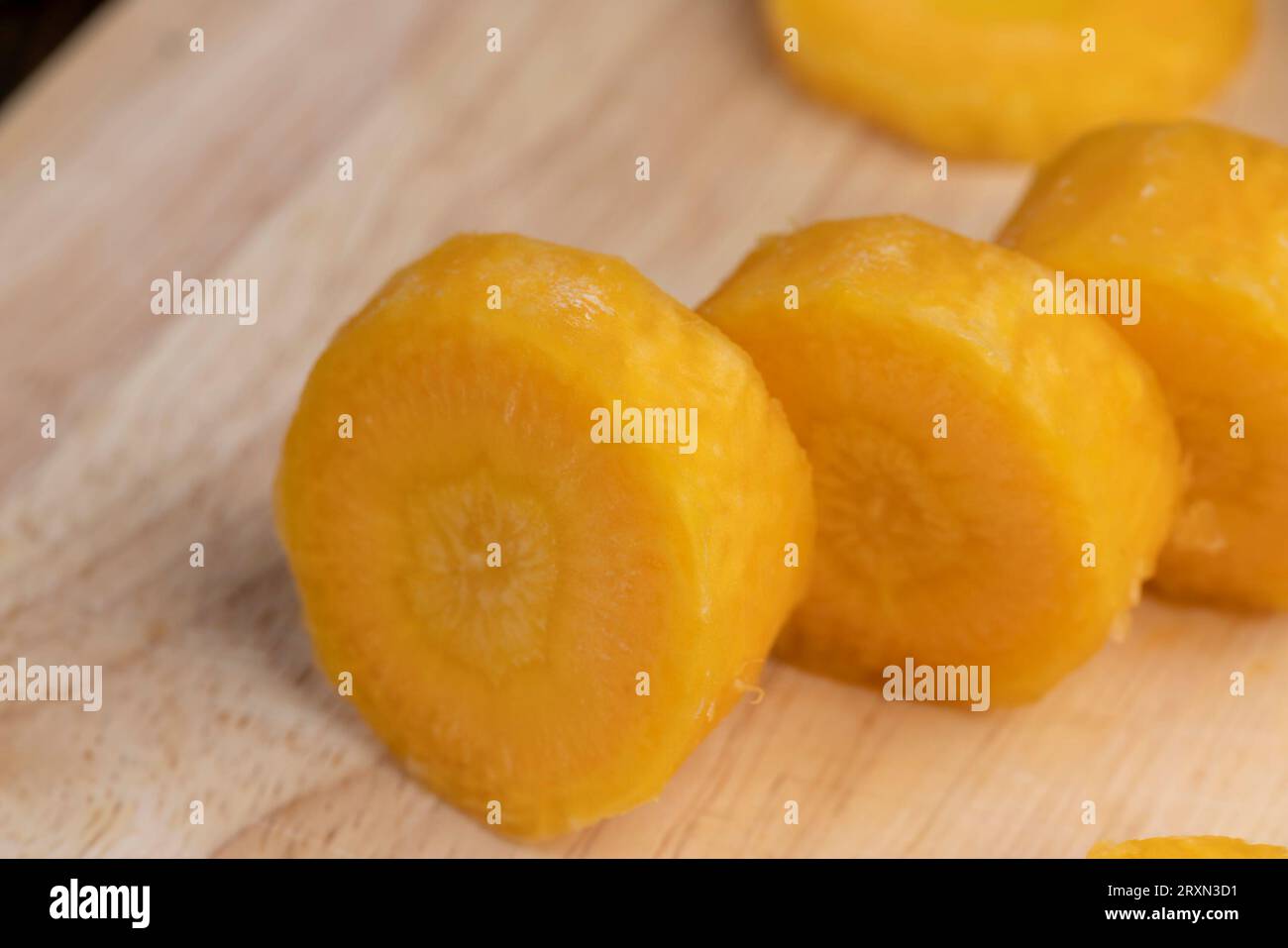 Sliced bright yellow carrots on the table, several peeled carrot roots ...
