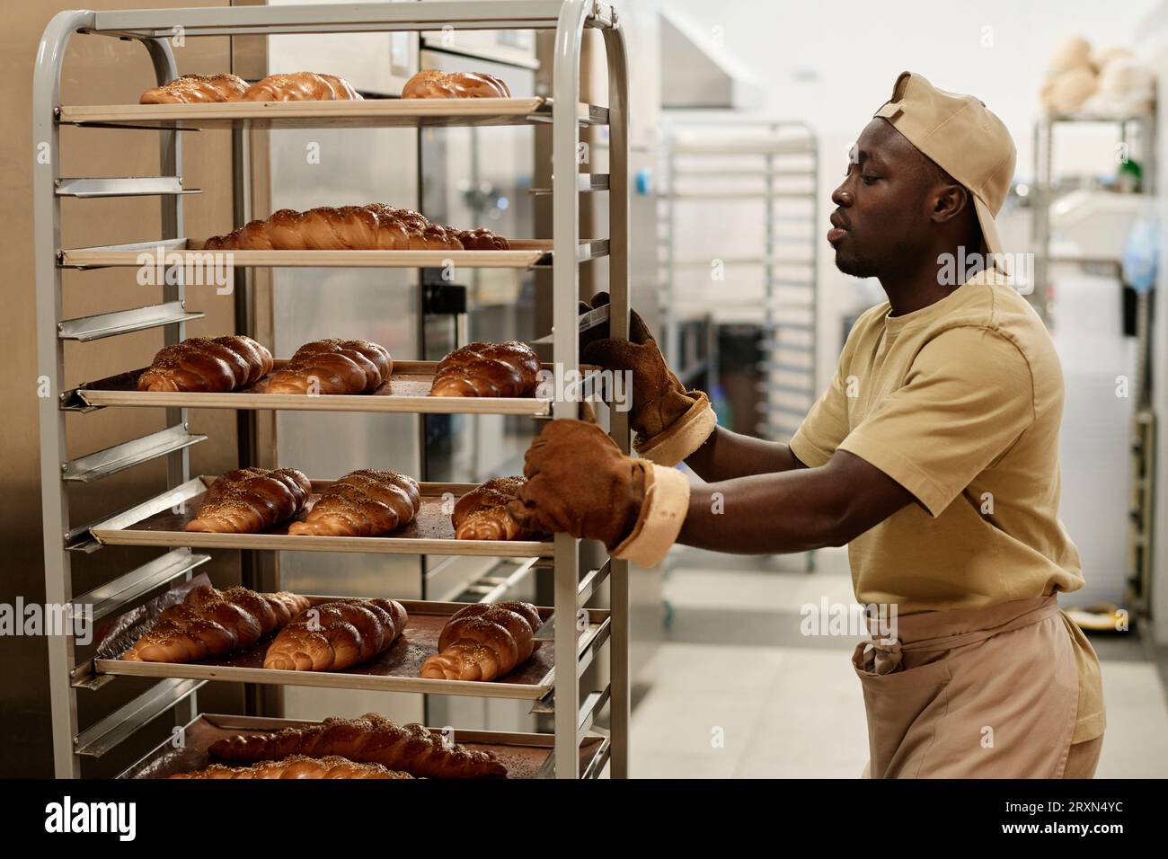 Side view portrait of Black young man moving shelves with freshly baked ...