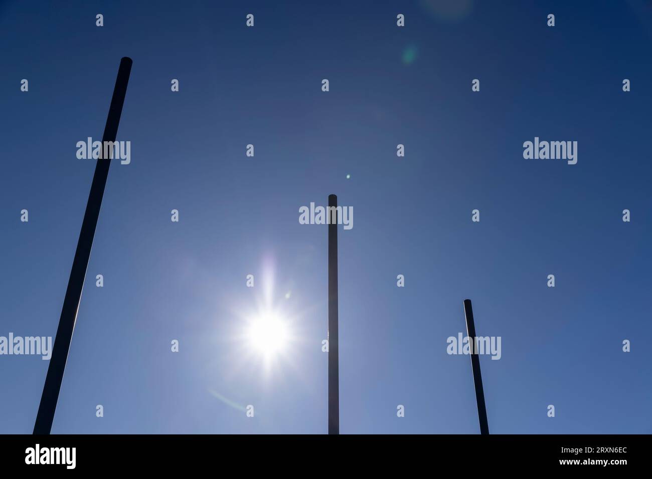 a group of empty metal flagpoles against a blue sky background, metal ...