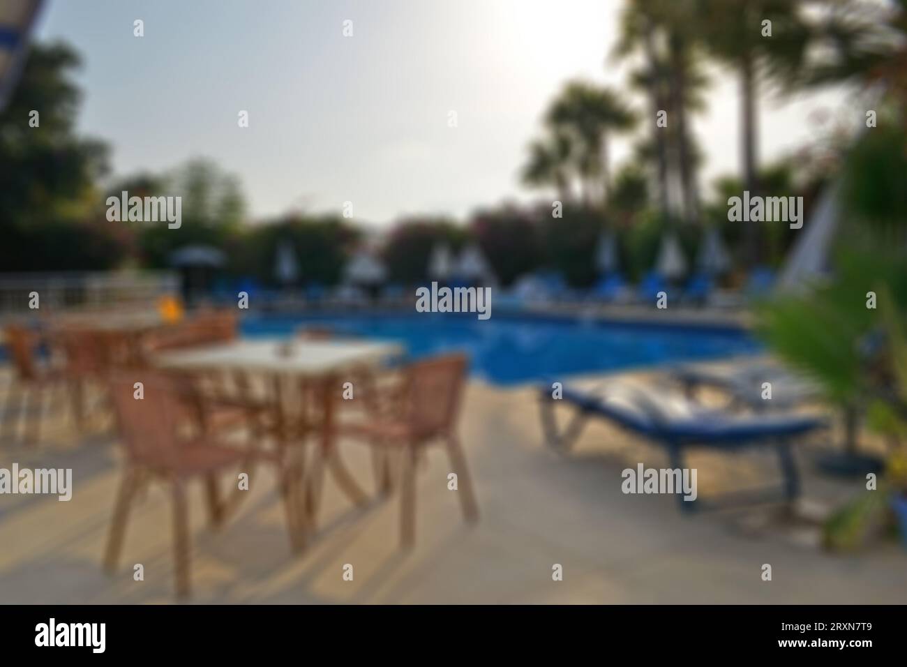 Blurred background of a beautiful sunset near a pool side with chairs ...