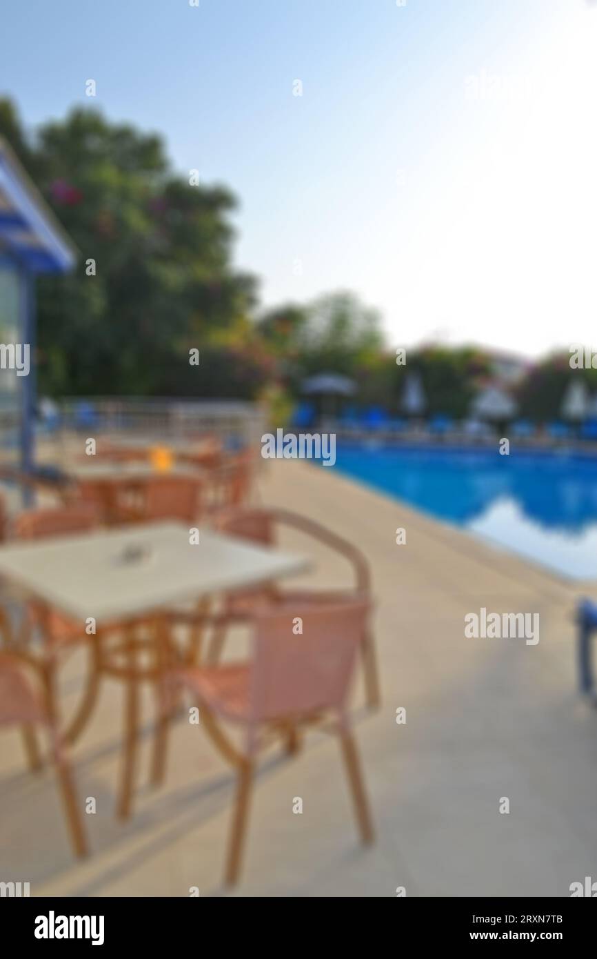 Blurred background of a beautiful sunset near a pool side with chairs ...