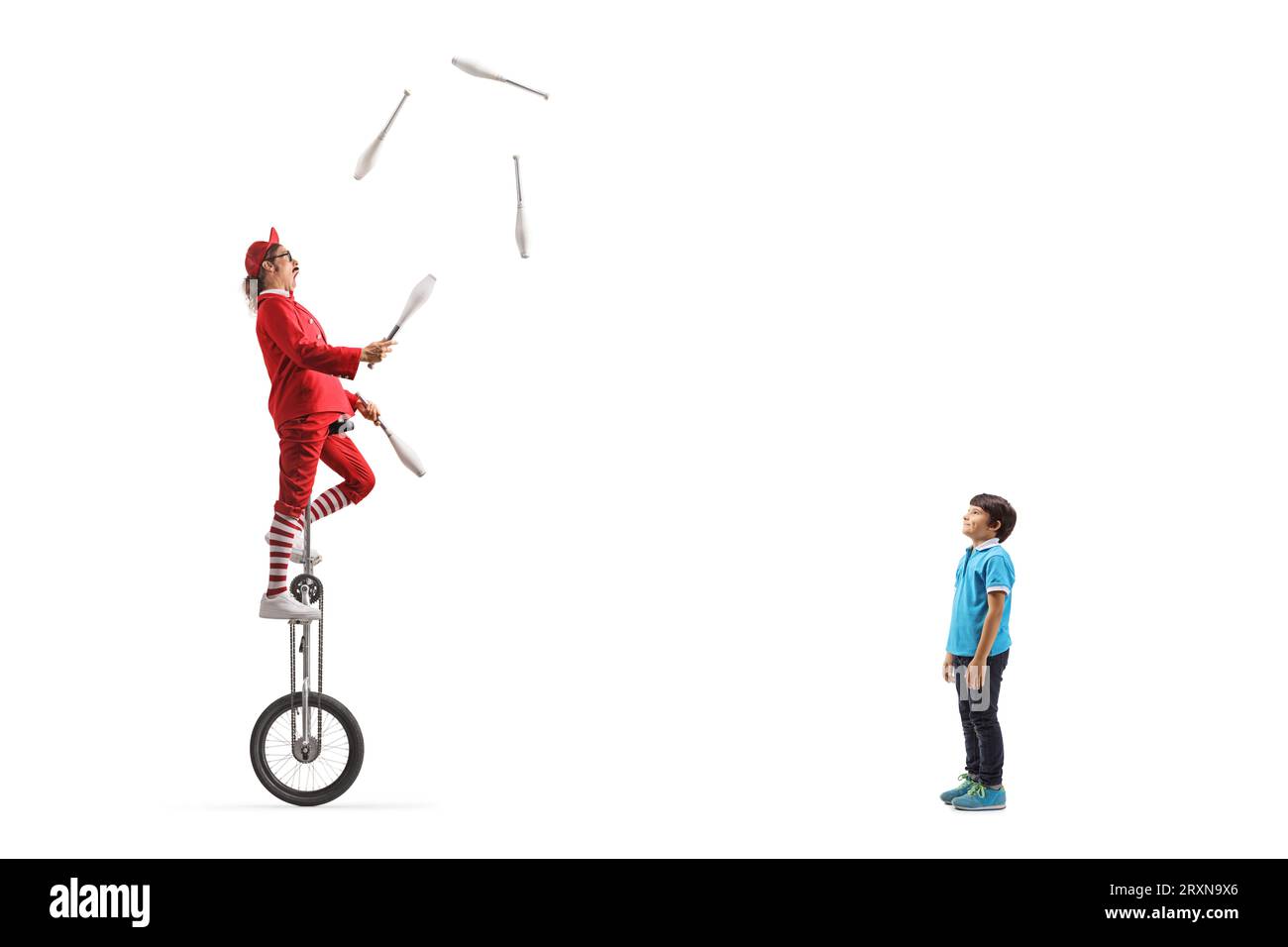 Child watching an acrobat riding a giraffe unicycle and juggling ...