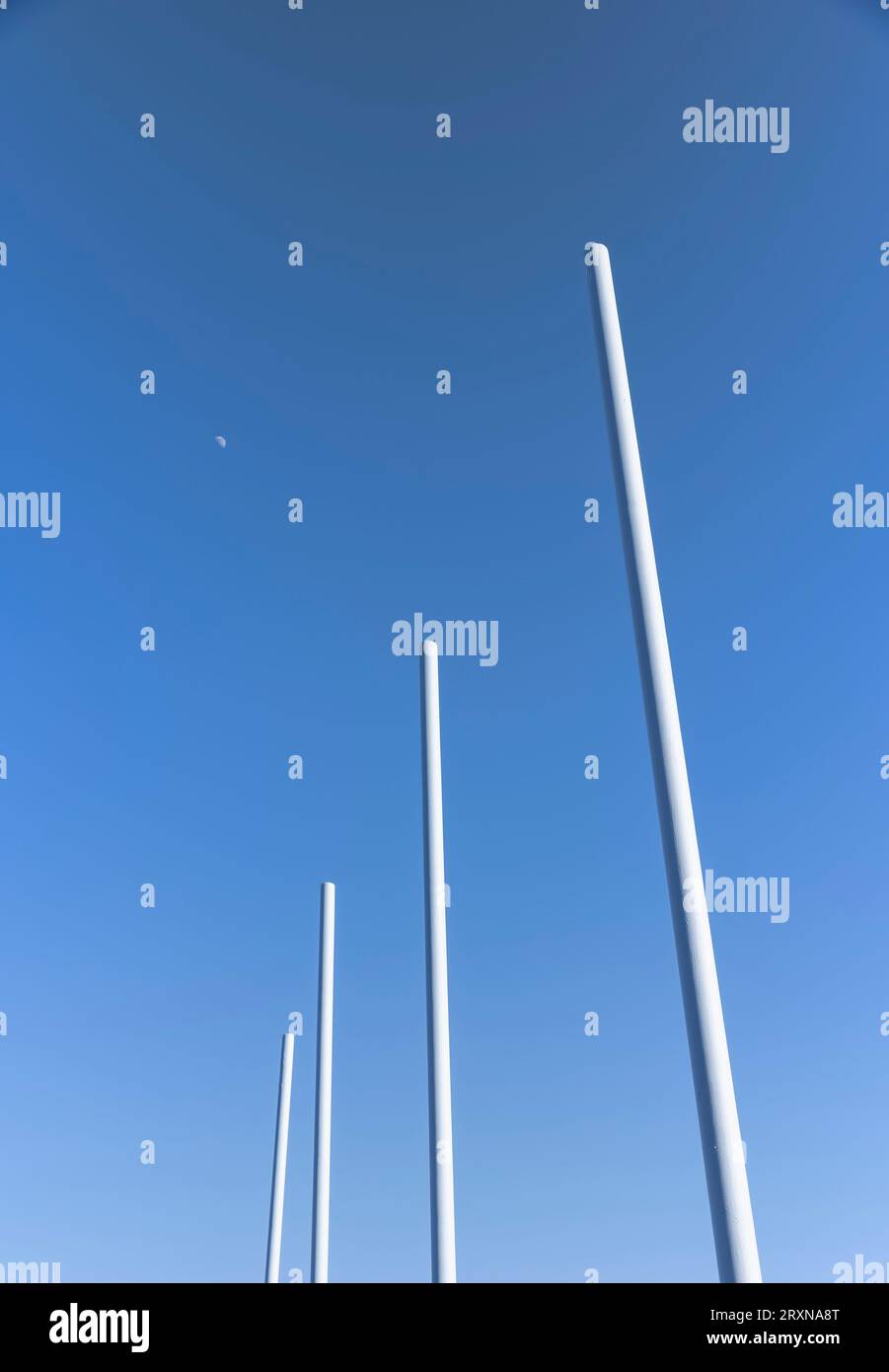 a group of empty metal flagpoles against a blue sky background, metal ...