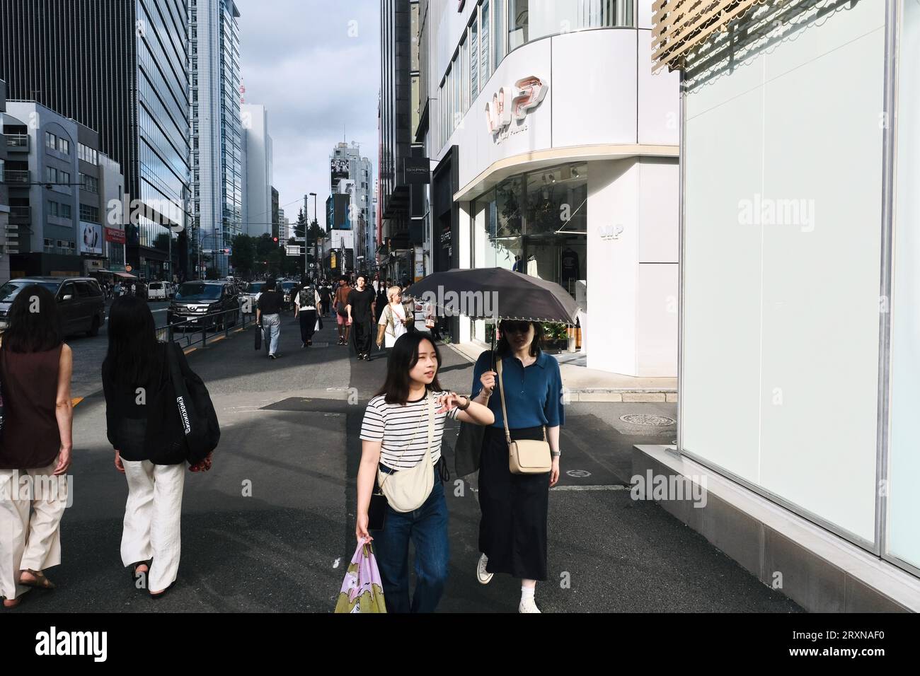Two women walk along the pavement in the high-end shopping district of ...