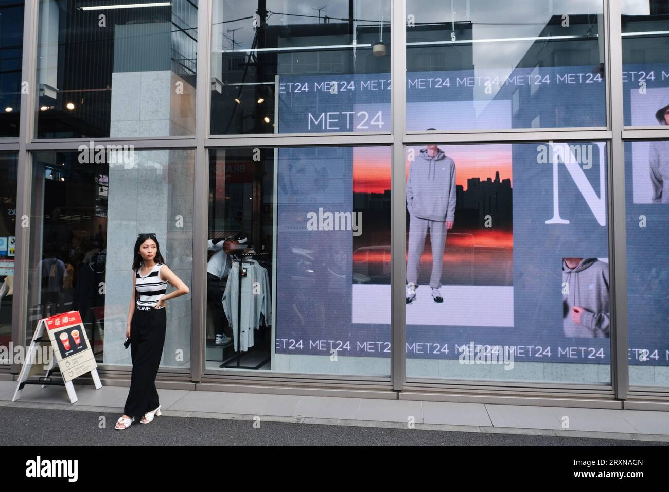 A young woman stands outside a fashion store in Omotesando, Tokyo ...